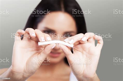 흡연을 중지 손에 담배를 들고 손가락으로 반으로 그것을 깨는 아름 다운 웃는 여자의 근접 촬영 초상화 종료 흡연 담배 개념