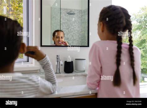 Biracial Brother And Sister In Pyjamas Brushing Teeth Together In The