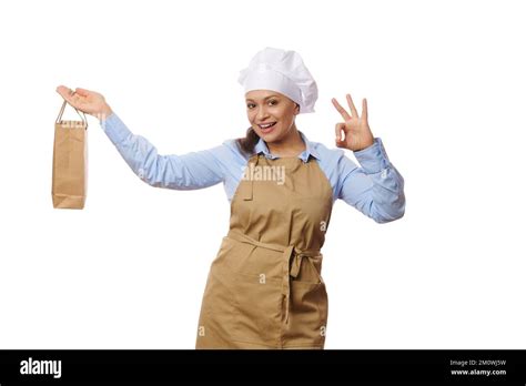 Pretty Woman Waitress In Chef Hat And Beige Apron Holds Paper Bag With