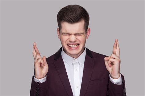 보라색 양복과 흰 셔츠에 희망 꿈 잘생긴 젊은 남자의 초상화 서 교차 손가락과 손가락 떨림으로 그의 눈을 폐쇄 25 29세에