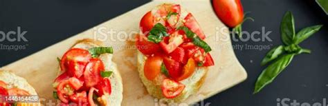 신선한 빨간 토마토와 바질 허브를 마당 집 뒤뜰 햇빛에 야외 나무 보드에 담은 이탈리아 브루 쉐타 배너 고전적인 이탈리아 음식