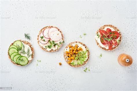 크림 치즈 무 토마토 병아리콩 오이 마이크로그린을 곁들인 바삭바삭한 메밀 빵 4개가 회색 돌 배경의 양피지 에 있는 양피지에서
