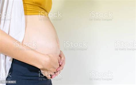 임산부가 서서 조심스럽게 배를 들고 두 번째 삼 분기 임신 아기가로드되고 공간을 복사하고 무거운 배를 잡습니다 건강관리와 의술에