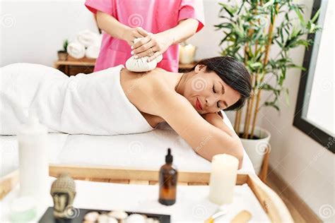 Middle Age Hispanic Woman Having Back Massage Using Thai Bags At Beauty