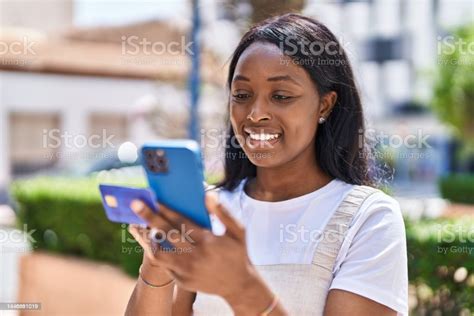 공원에서 스마트 폰과 신용 카드를 사용하는 젊은 아프리카 계 미국인 여성 Brand Name Mobile Payment에 대한