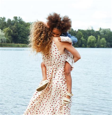 Young European Mother Holds Her Six Year Old Dark Skinned Daughter In