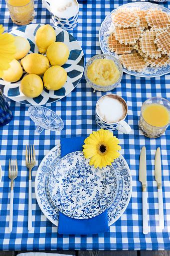 자연에서 피크닉 파란색 금식 칼 세라믹 플레이트 체크 무늬 식탁보 와플 디저트 레모네이드 및 과일 커피 한 잔의 우아한 테이블 세팅 꽃병에 노란색 메리 골드 꽃입니다 맨 위
