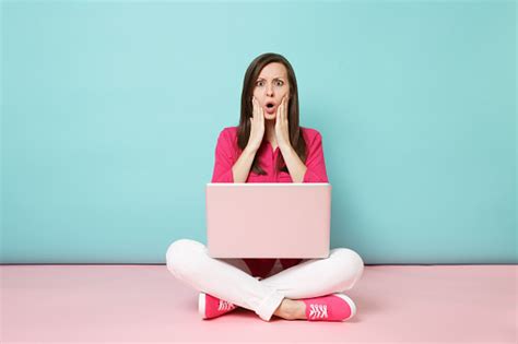 핑크 블루 파스텔 벽 배경 스튜디오에 고립 된 노트북 Pc를 사용 하 여 바닥에 앉아 장미 셔츠 블라우스 흰색 바지에 젊은