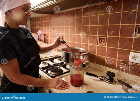 Housewife Pours Tomato Juice Into A Sterilized Jar Preparing Homemade
