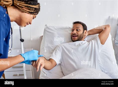 Young African American Nurse Inserting Catheter Into Arm Of Her Sick