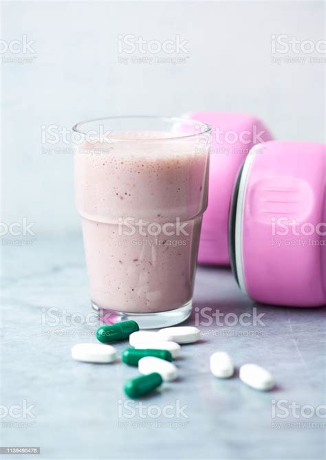 우유와 라즈베리가 포함 된 단백질 셰이크 유리 Bcaa 아미노산 L카 르 니 틴 캡슐 및 핑크 덤 벨 배경 스포츠 영양 돌 나무