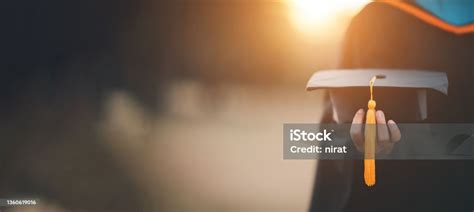 노란 술이 달린 검은 색 모자를 들고 있는 졸업생들은 일몰을 손에 들고 졸업장을 들고 서 있다 졸업식 대학의 졸업생을 축하했다 대학교에 대한 스톡 사진 및 기타 이미지