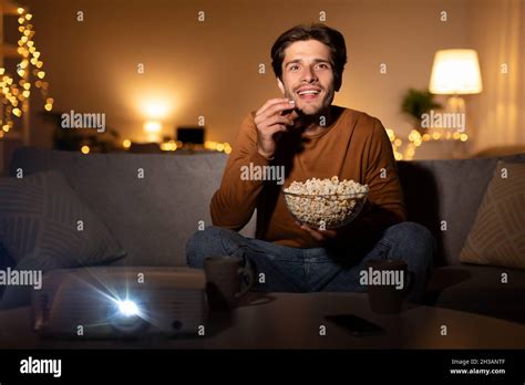 Excited Man Watching Movie Using Projector Eating Popcorn At Home Stock
