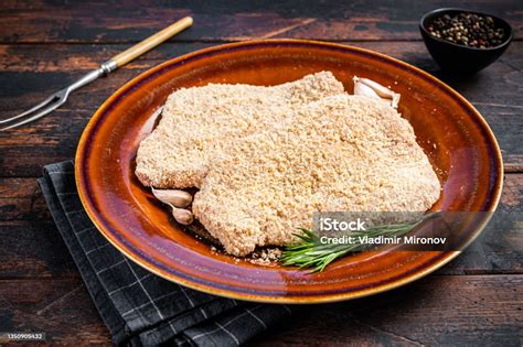 ハーブと素朴なプレートに生のパンドドイツのウィーナーシュニッツェル暗い木製の背景トップビュー チキンフライのストックフォトや画像を多数ご
