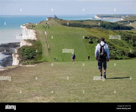 Tourists On The Beachy Head Coast Path With Belle Tout Lighthouse And
