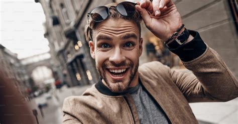 캐주얼 웨어를 입은 잘생긴 청년의 자화상은 야외에 서서 웃고 얼굴을 만든다 사진 Unsplash의 미소 이미지