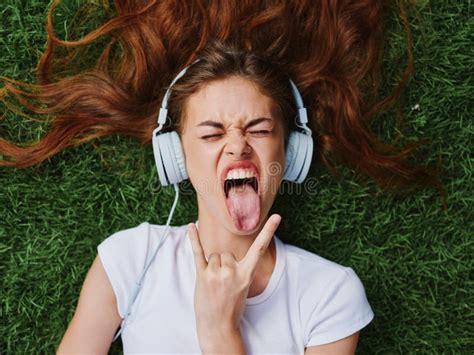 Woman Lying On Green Grass With Headphones In Hand Spreading Her Hair