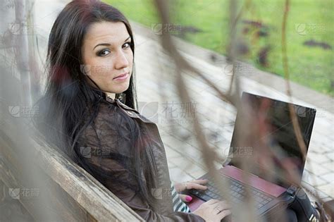 年轻漂亮的黑发学生侧面坐在长椅上