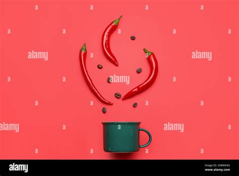 Mug With Hot Chili Peppers And Coffee Beans On Red Background Stock