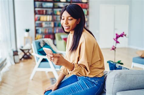 로프트 아파트에서 웹 통신 중에 모바일 Sms를 보내기 위한 텍스트를 입력하는 예쁜 흑인 여성 밀레니얼 세대 스마트폰 응용 프로그램에 대한 어두운 피부 업데이트 알림을 가진