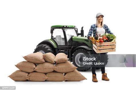 채소와 함께 상자를 들고 트랙터와 삼베 자루 더미 앞에서 포즈를 취하는 여성 농부 30 34세에 대한 스톡 사진 및 기타 이미지 30 34세 가지 채소 고추류