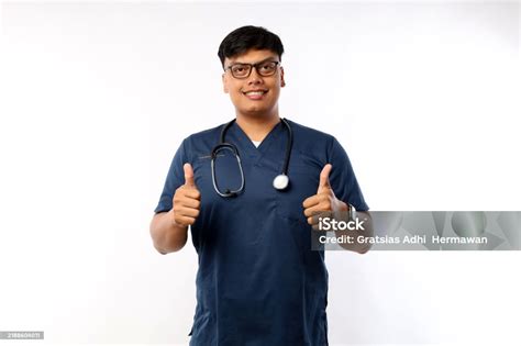 의료 종사자 개념입니다 미소 예쁜 아시아 남성 의사 스크럽 간호사는 모든 좋은 것을 보장하고 승인에 엄지 손가락을 보여주고 동의하거나 무언가를 좋아하고 흰색 배경을