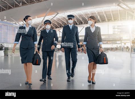 Two Pilots And Two Flight Attendants Walking Through The Terminal Stock