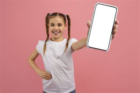 girl showcasing smartphone screen to viewer pink background stock