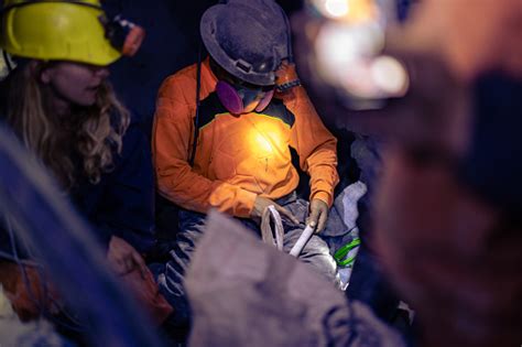Miner Preparing Explosive With Dynamite While Small Group Of Tourists