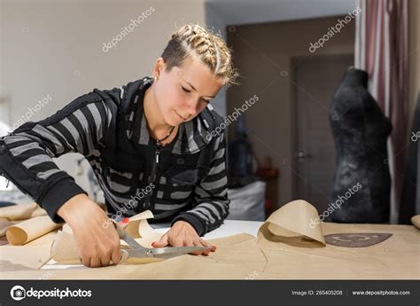 Blonde Woman Seamstress Cuts From Craft Paper Pattern For Making Stock