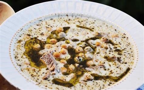 A White Bowl Filled With Soup On Top Of A Wooden Table