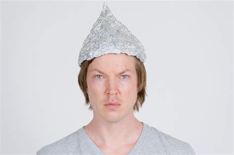 Retrato de joven guapo hombre llevando papel de aluminio sombrero como teoría de la