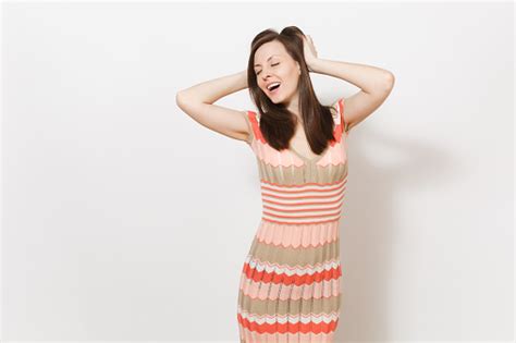 라이트 베이 지와 핑크 꽃무늬 드레스 웃 고 있는 아름 다운 젊은 갈색 머리 여자 즐길 고 흰색 바탕에 스튜디오에 머리 근처에 손을 잡고 좋은 분위기의 개념입니다 광고에 대