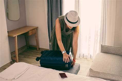 밀짚 모자 포장 된 여행 가방 여권을 가진 중반 성인 여성이 여름 방학을 마치고 호텔 방에서 기다리고 있습니다 공휴일에 대한 스톡 사진 및 기타 이미지 Istock