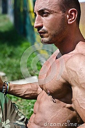 Handsome Muscular Bodybuilder Shirtless Sitting On The Grass Royalty