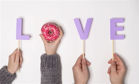 보라색 글자로 만든 Love라는 단어와 흰색 배경에 분홍색 으로 채워진 도넛의 상단 보기 발렌타인 데이 카드 낭만주의에 대한