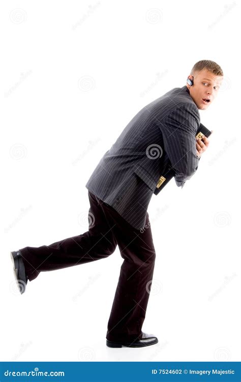 A Scared Businessman Hides Away From A Giant Red Alarm Clock Standing