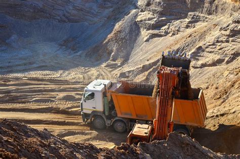 Excavator Bucket Loading Sand Into The Body Of A Heavy Dump Truck Stock