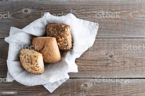 베이지 색 린넨 냅킨에 해바라기 씨 치아 오트밀을 곁들인 신선한 빵 3개가 있습니다 나무 배경입니다 공간을 절약합니다 신선한