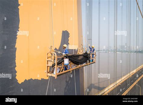 Chinese Workers Labor At The Construction Site Coating The Pillars Of
