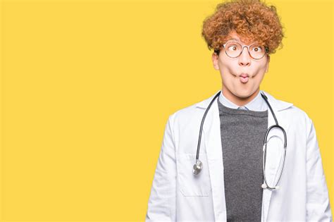 의료 입고 젊은 잘생긴 의사 남자 코트 입술 고 우 스 꽝 스러운 제스처와 함께 물고기 얼굴 만들기 재미 있는 식입니다 건강관리와 의술에 대한 스톡 사진 및 기타 이미지
