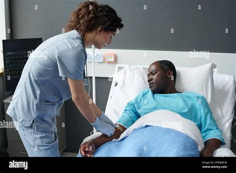 Jeune infirmière qui fait un compte gouttes pour un patient malade elle insère un cathéter dans