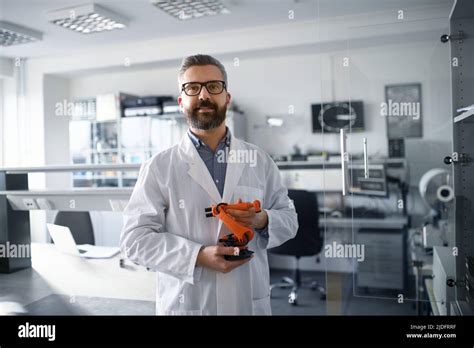 Robotics Engineer Holding Modern Robotic Arm Standing And Looking At Camera In Laboratory