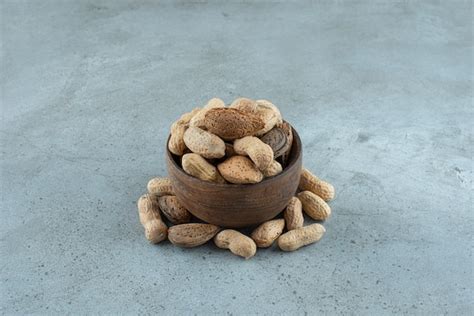 돌 배경에 놓인 바삭한 땅콩 나무 그릇 무료 사진
