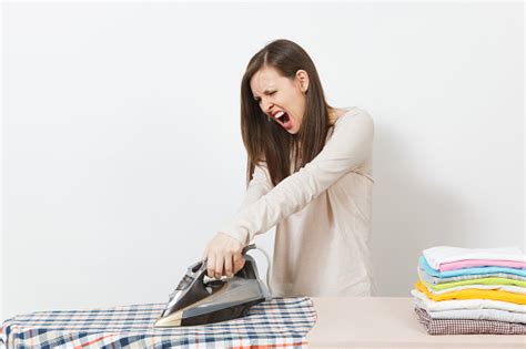 화가 공격적 비명 주부 남편의의 셔츠를 다림 질 하는 가벼운 옷에 다림 질 보드와 철에 의류 흰색 배경에 고립 된 여자입니다