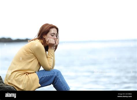 Sad Casual Woman Thinking Alone Sitting On The Beach Stock Photo Alamy