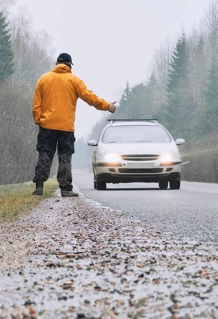 Premium Photo A Man In An Orange Jacket Stands On The Side Of A Road