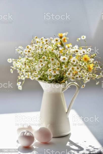흰색 표면에 흰색 용기와 부활절 달걀에 필드 카모 마일의 꽃다발 신선한 정원 꽃 꽃다발 봄 초원 꽃 여름철 부활절 카드 7월에