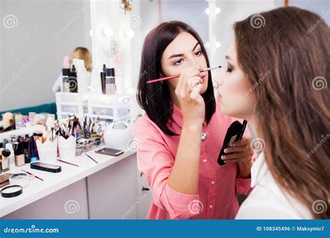 Make Up Artist Does Makeup To A Beautiful Girl In A Beauty Salon Stock