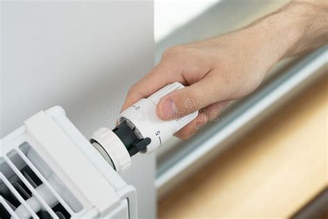 The Man Adjusts The Radiator Thermostat To The Maximum Temperature In The Room Stock Image